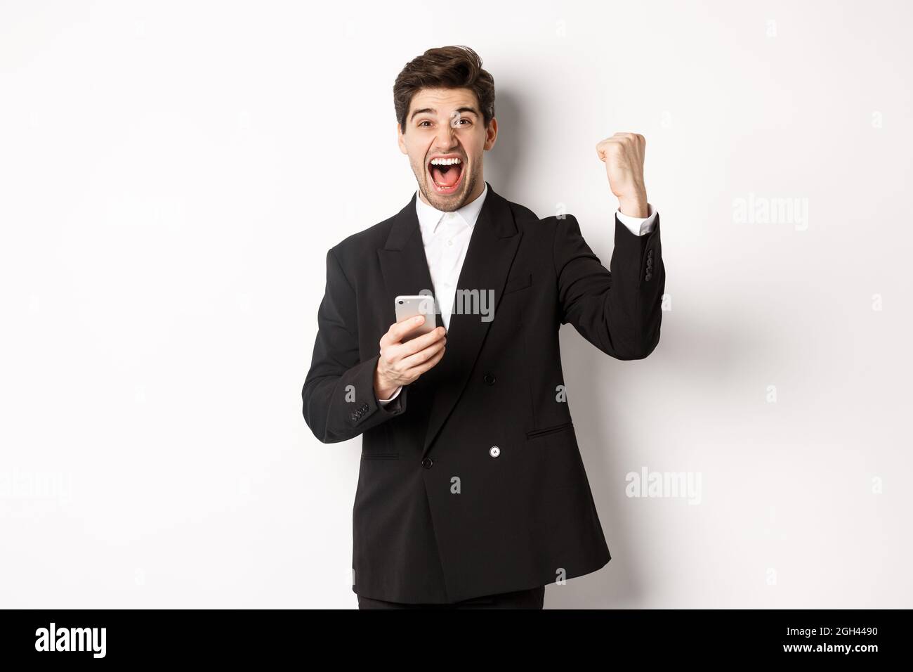 Portrait of happy handsome man in suit, rejoicing, achieve goal on ...
