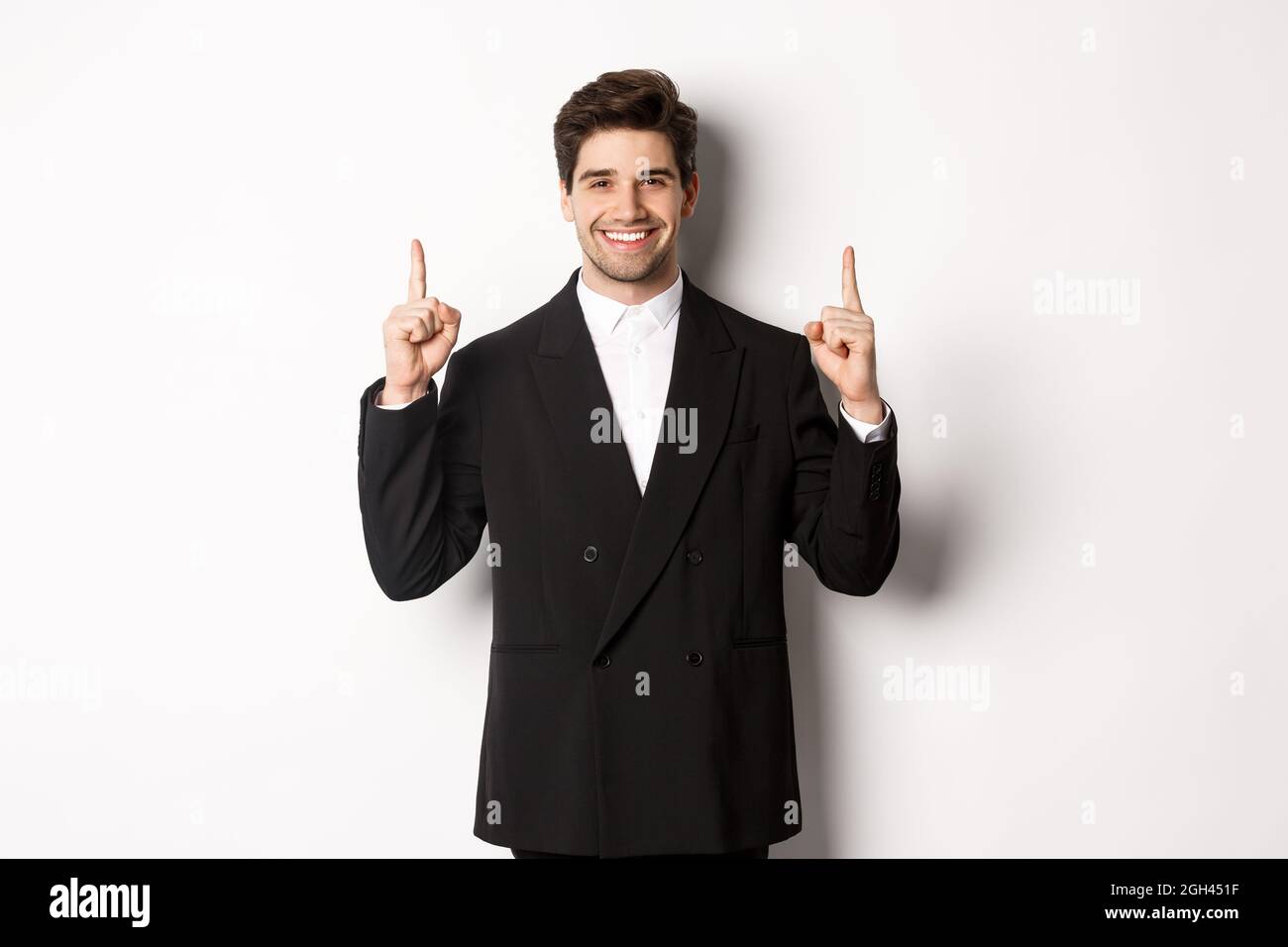 Portrait of attractive caucasian man in stylish black suit, pointing ...
