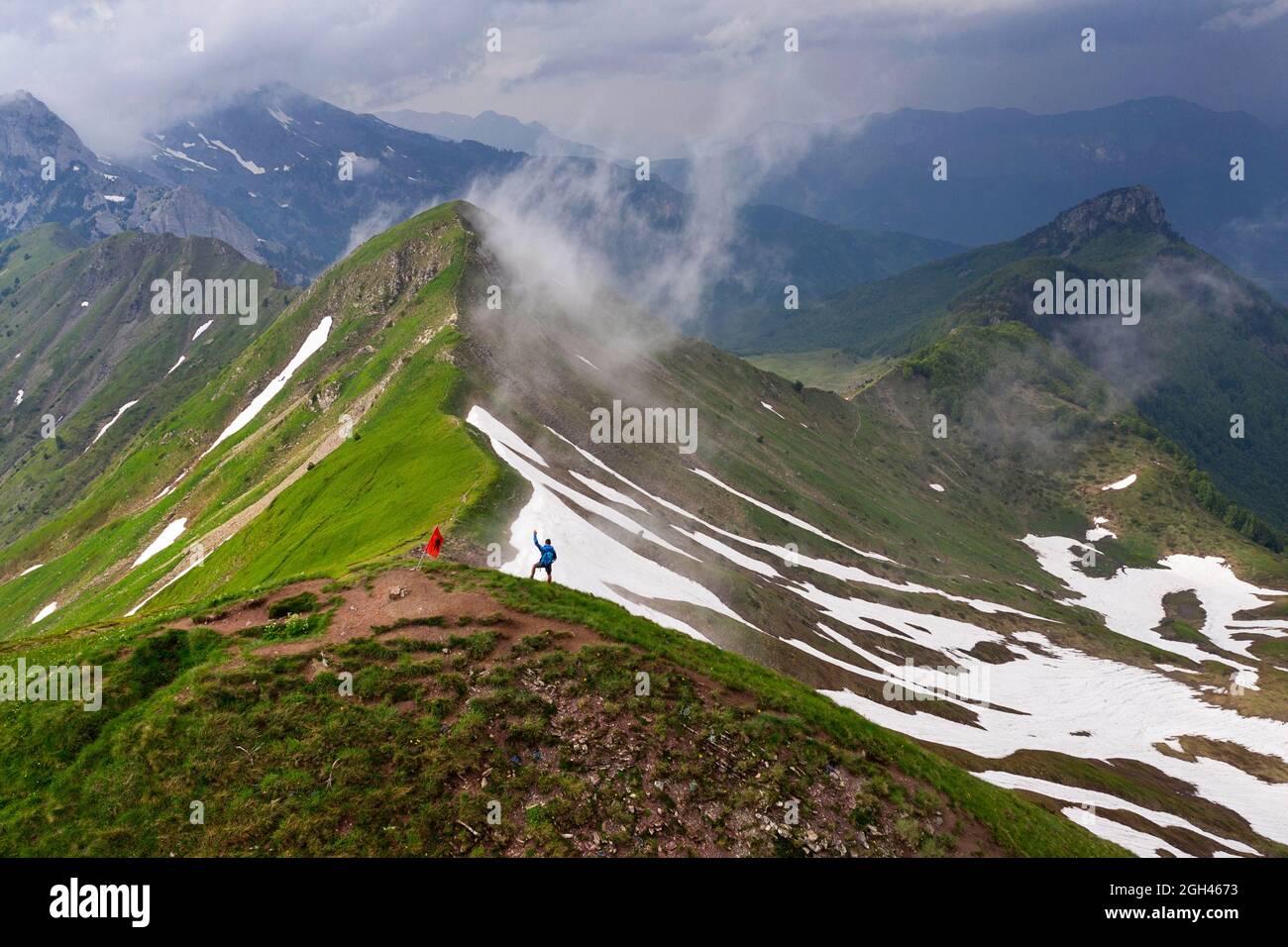 A hiker standing on top of the Maja e Vajushës peak (talijanka peak) in ...