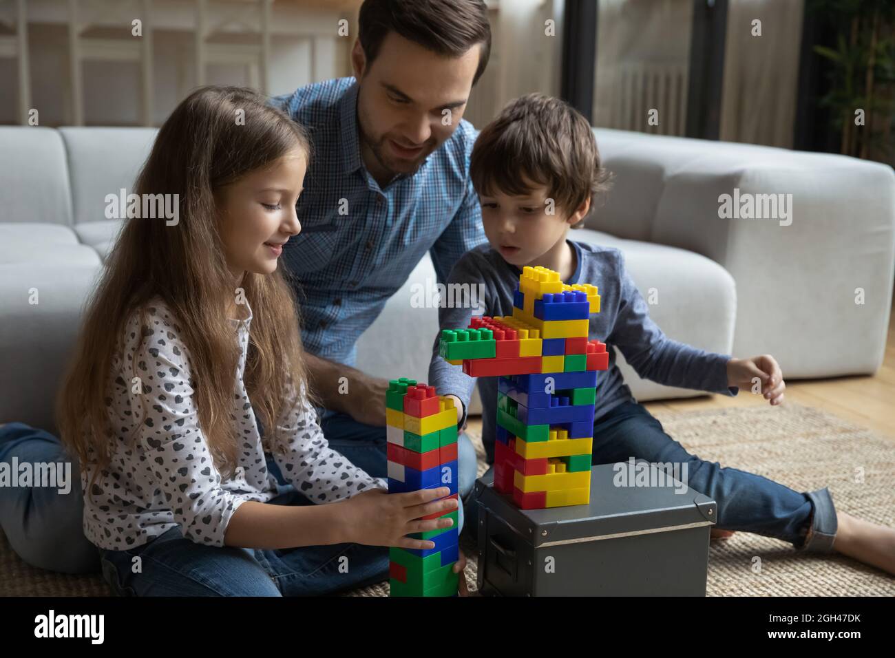 Dad teaching son and daughter to build tower from blocks Stock Photo ...