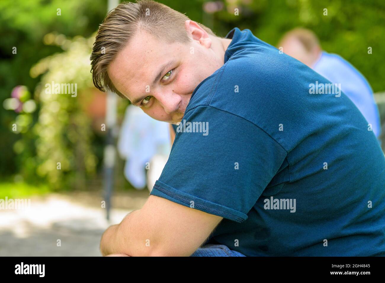 Friendly young man giving the camera a coy smile with laughing eyes as ...