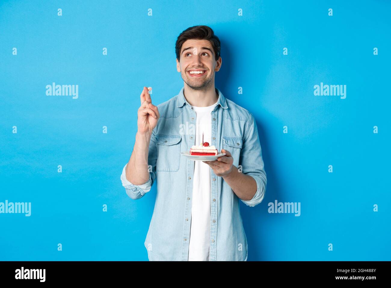 Handsome man making a wish, celebrating birthday, holding b-day cake ...