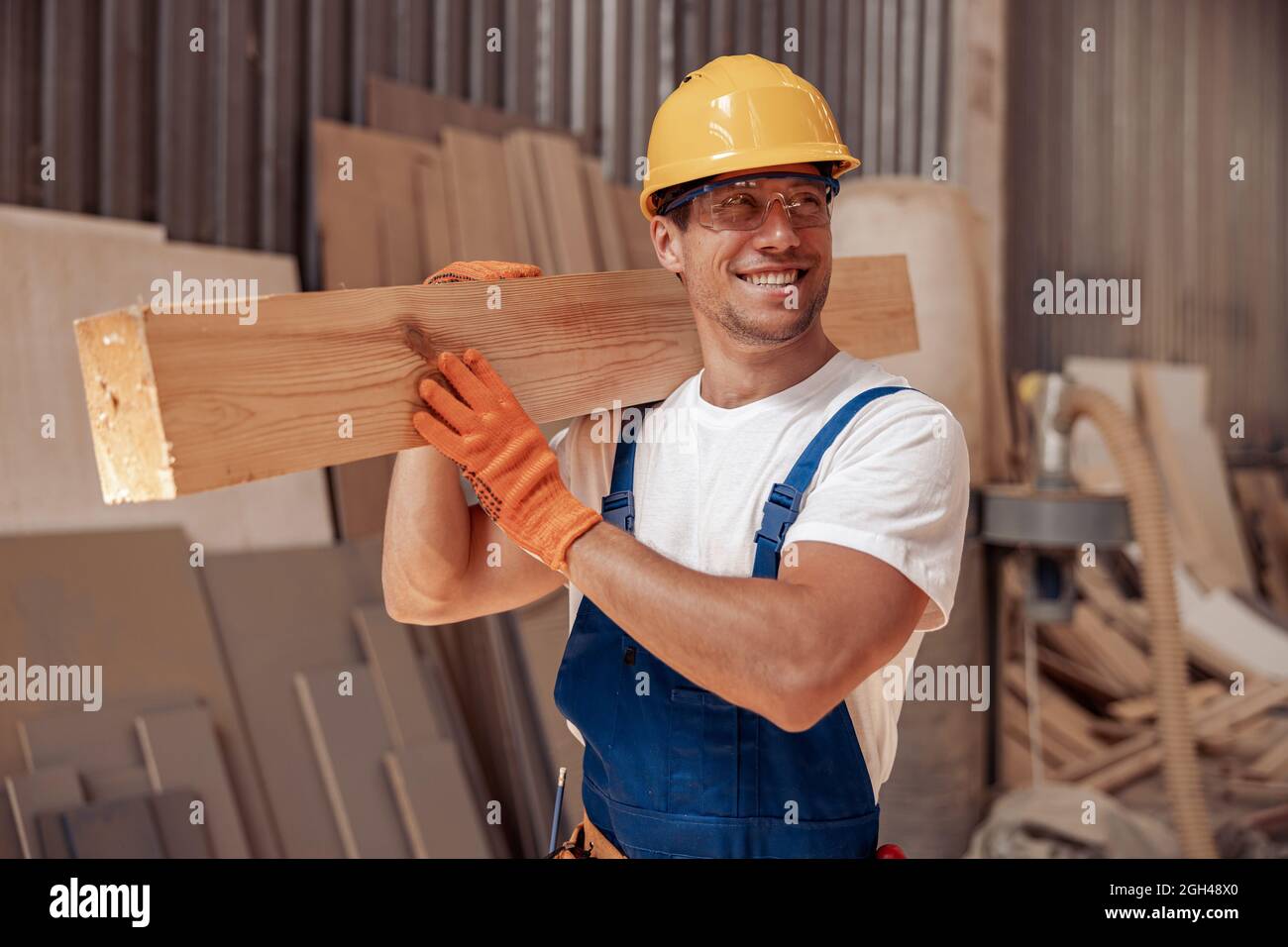 Cheerful worker carrying timber wood plank at construction site Stock ...