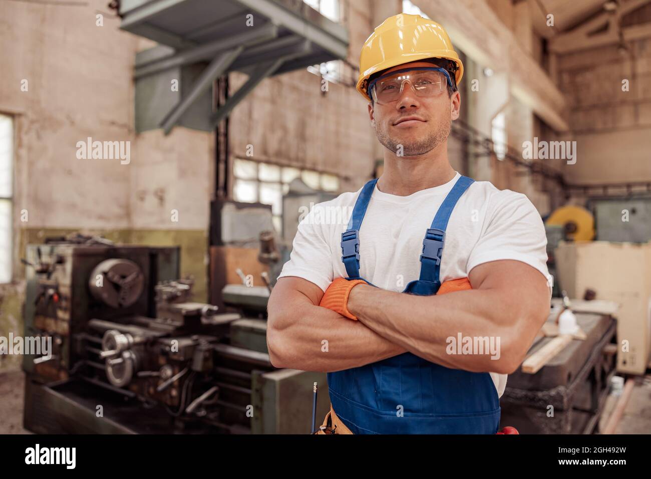 Athletic male builder in construction helmet standing in workshop Stock ...
