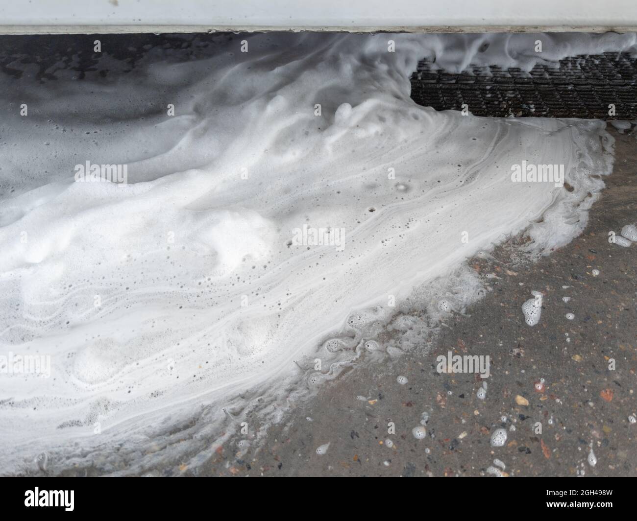 Soap sud waste flows to floor drain grid in car washing garage. Full ...