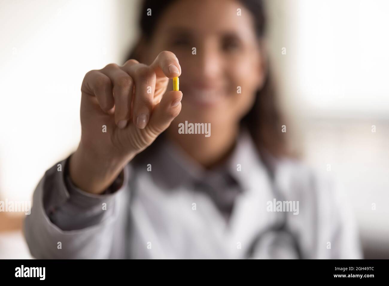 Happy female doctor showing drug, holding yellow pill at camera Stock ...