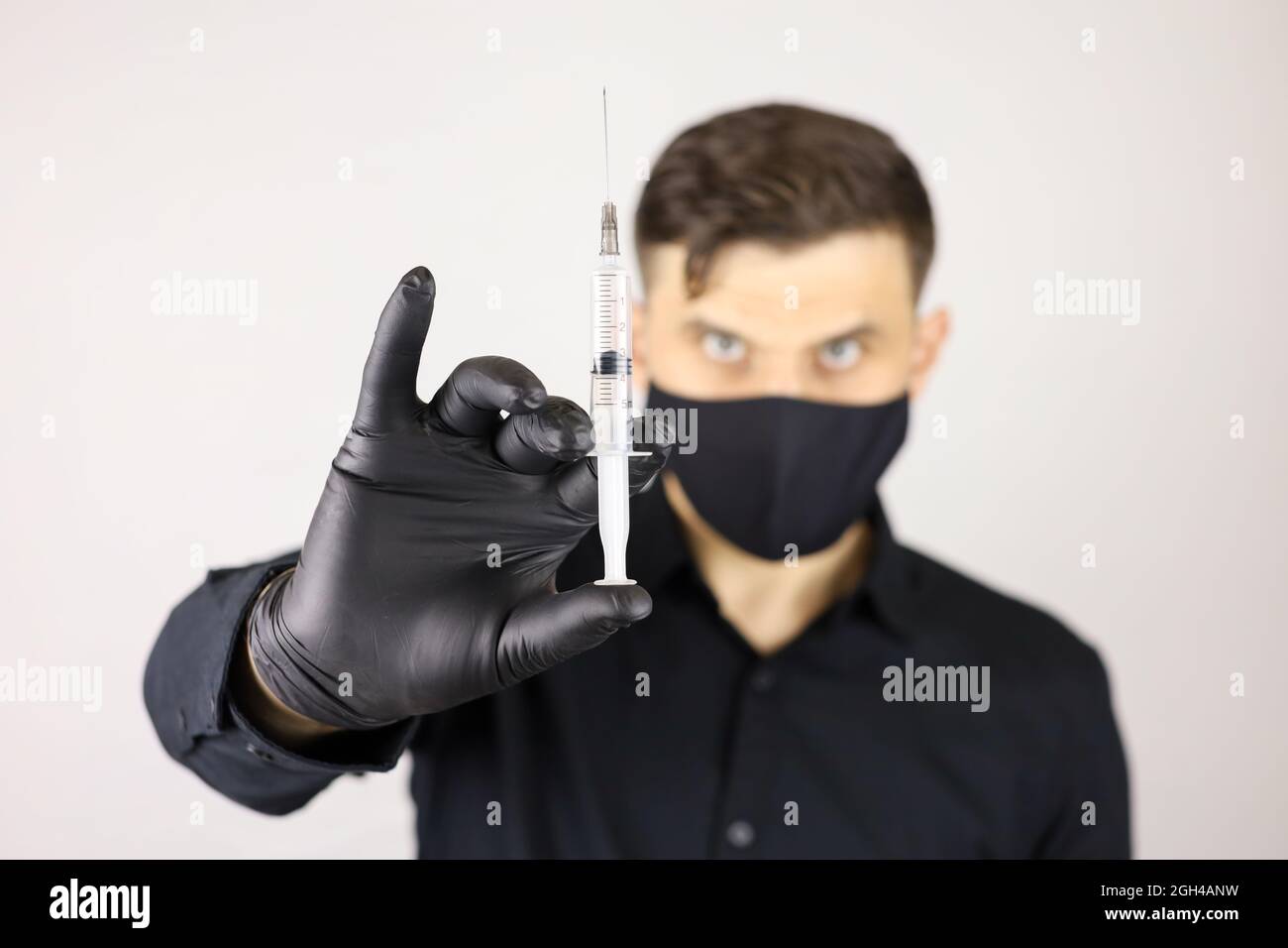 a man wearing black medical gloves and a protective mask holds an ...