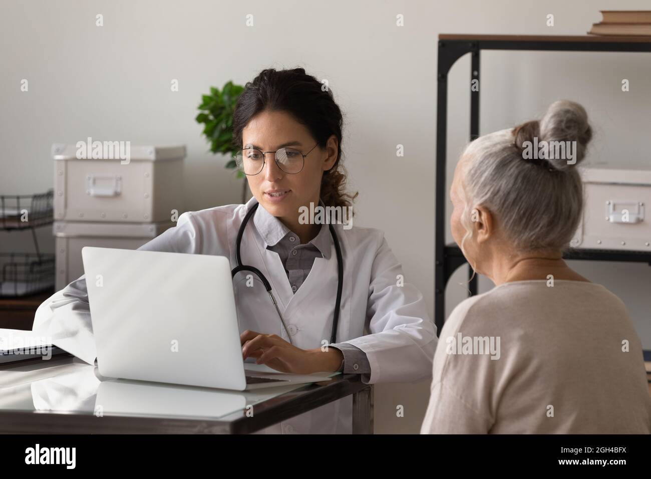 Serious young female doctor meeting with elderly patient in office ...