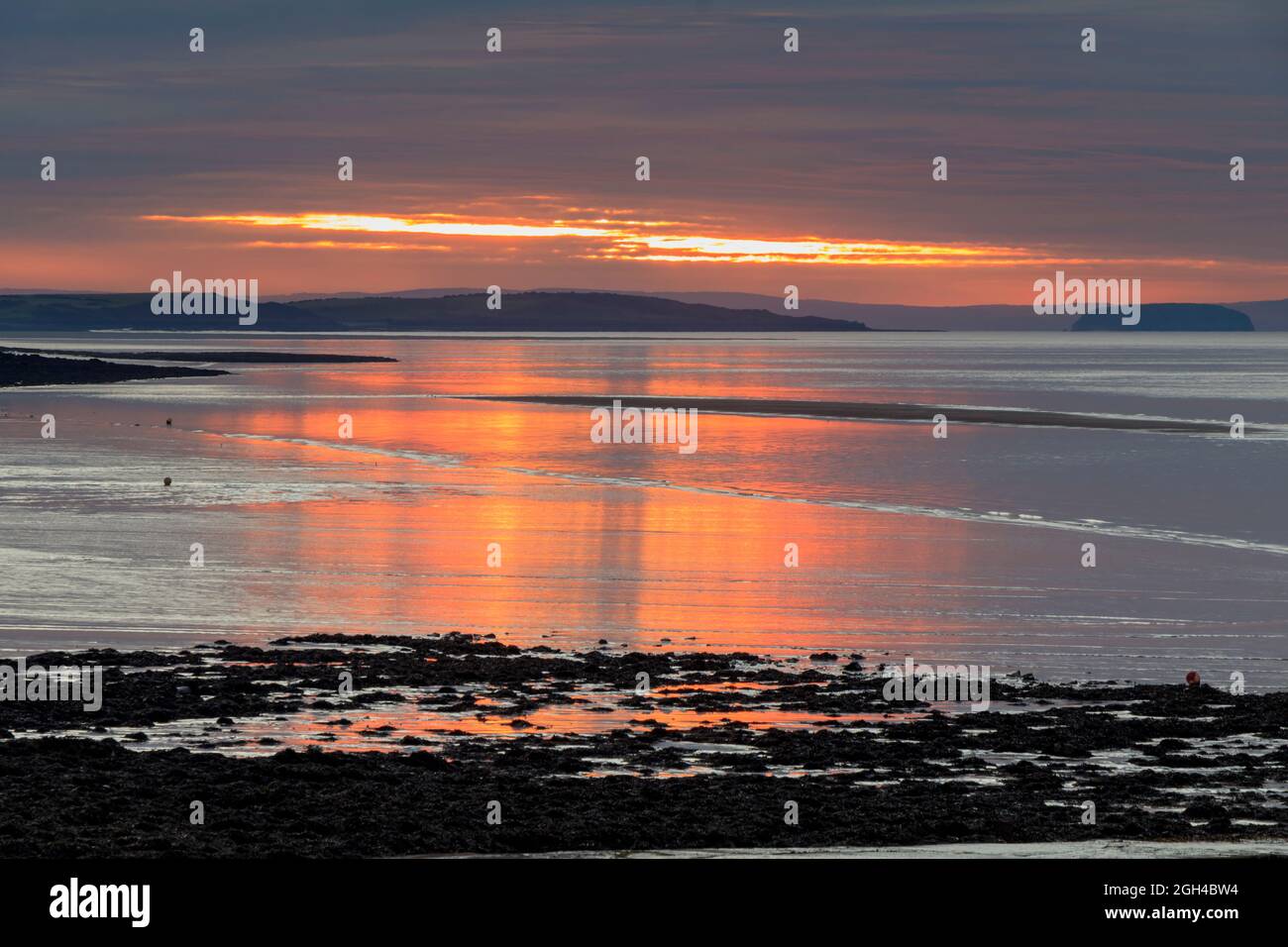 The setting sunlight reflecting onto the sea and mud Stock Photo - Alamy