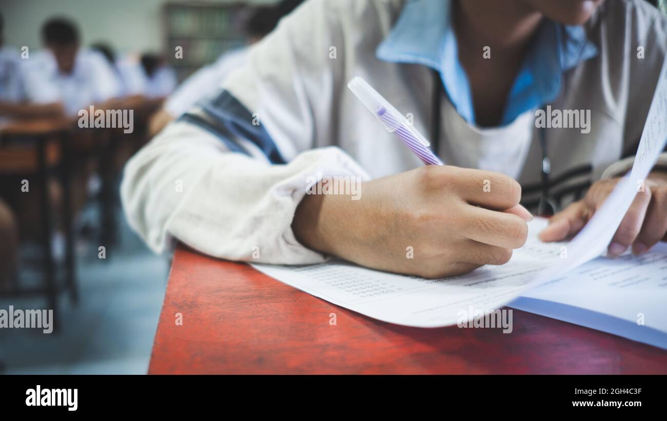 Students writing and reading exam answer sheets exercises in classroom ...