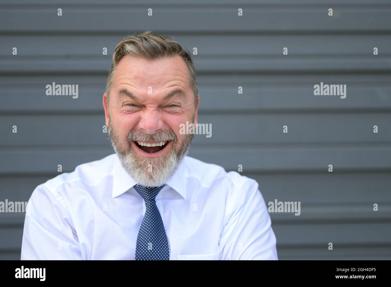 Businessman pulling a funny face screwing up his eyes with an ...