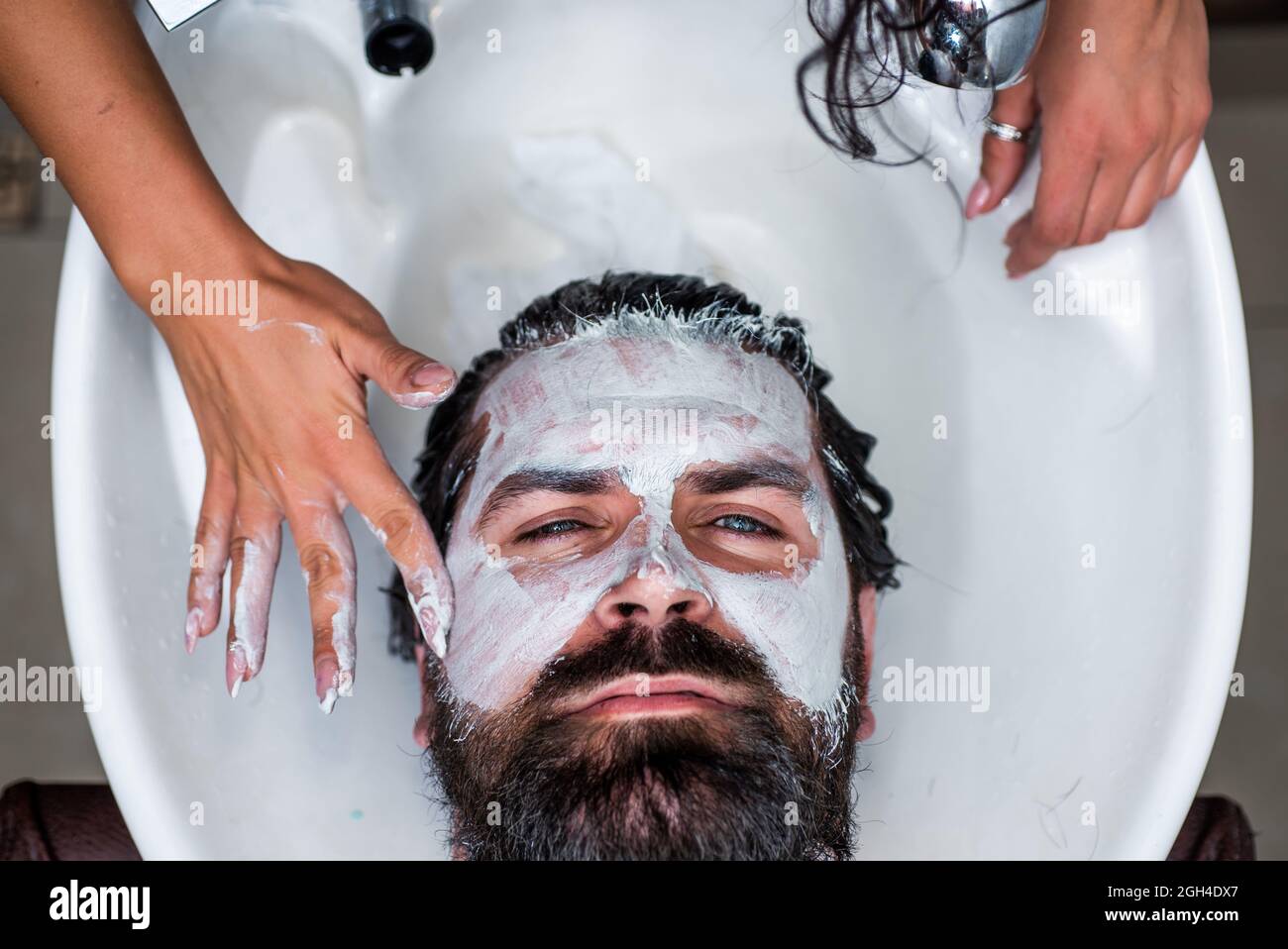 Hairdresser washes client man head in barbershop and use foam cream ...