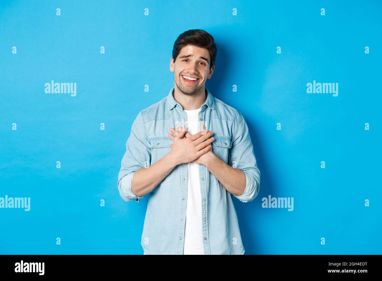 Portrait of flattered handsome man thanking you, holding hands on heart ...