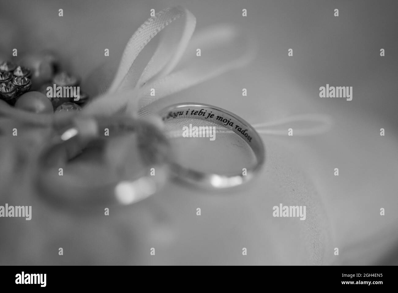 A selective focus grayscale shot of wedding rings on a white surface ...