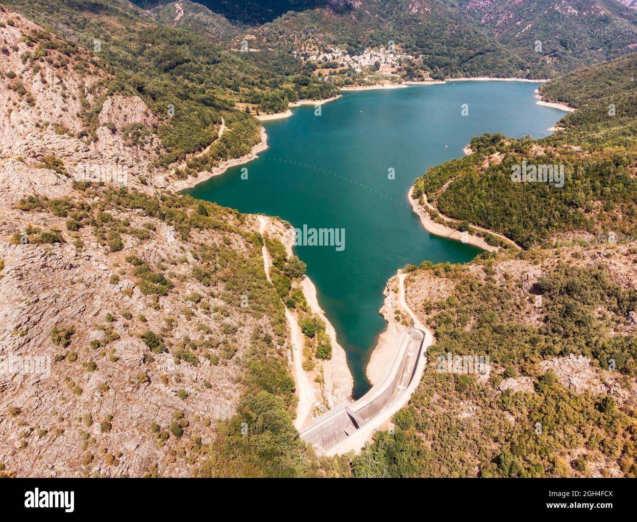 Aerial view of the dam wall at Lac de Tolla and the village of Tolla in ...