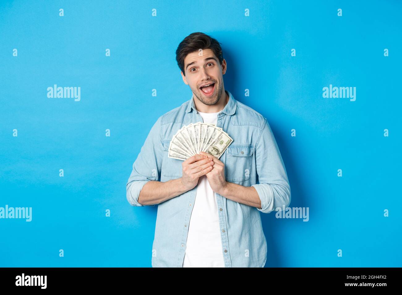 Smiling greedy guy hugging money and smiling, unwilling to share ...