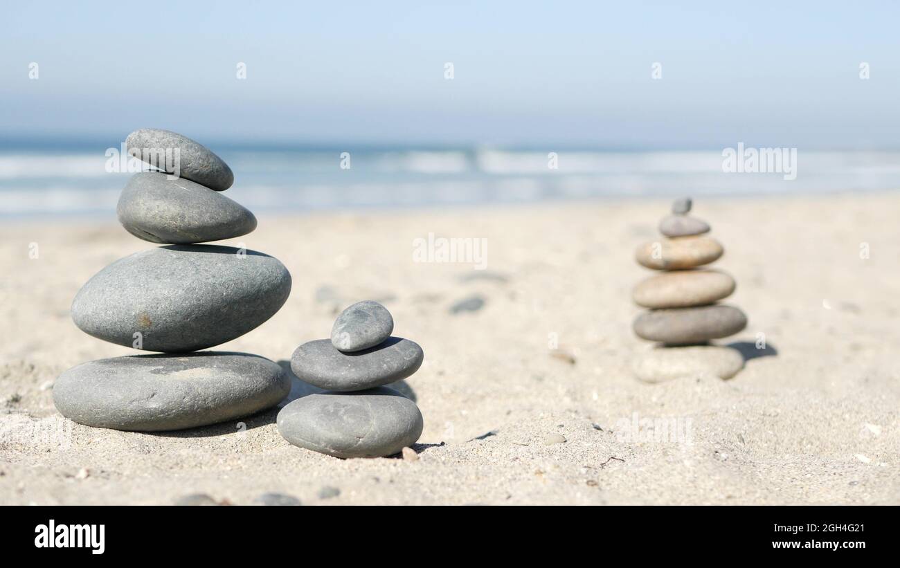 Rock balancing on ocean beach, stones stacking by sea water waves ...