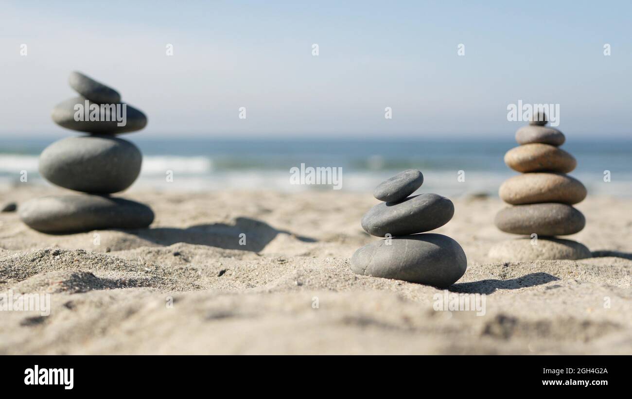 Rock balancing on ocean beach, stones stacking by sea water waves ...