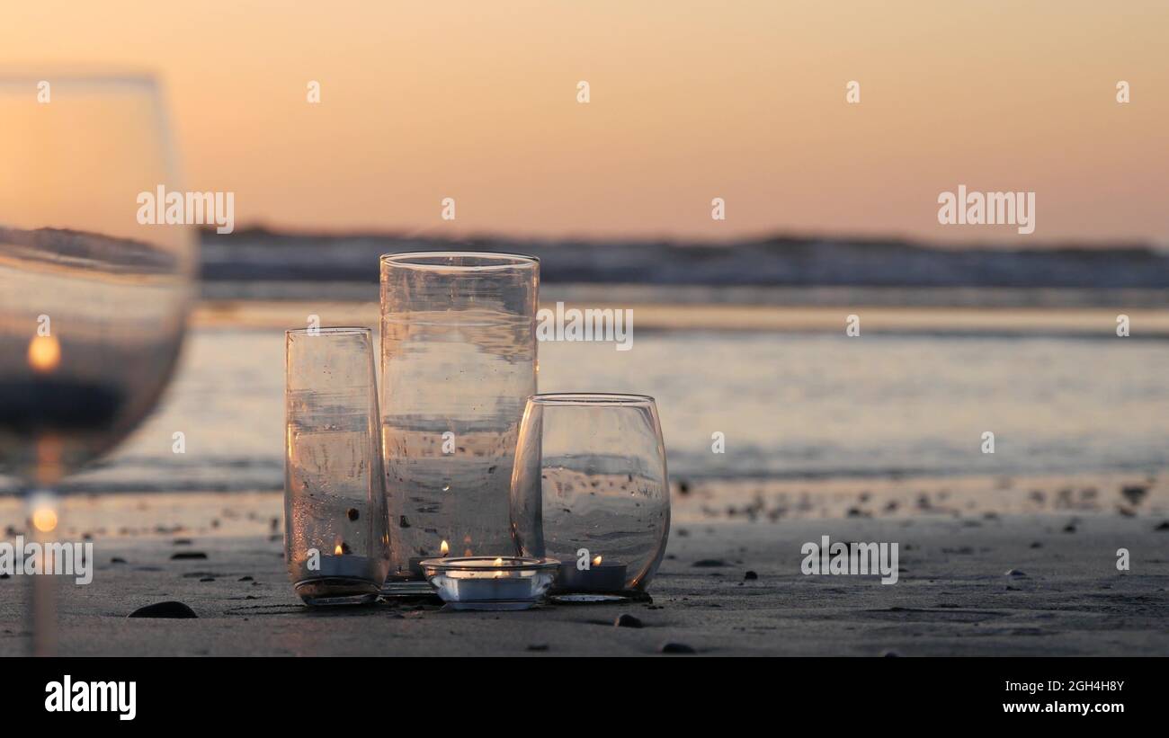 Candle flame lights in glass, romantic beach date by California ocean ...