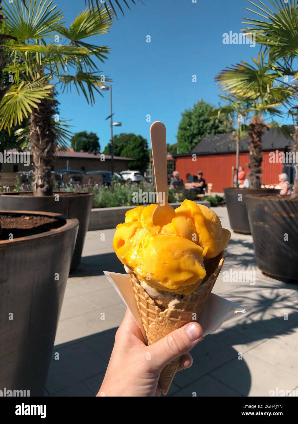 A young woman holding a mango ice cream cone outdoors in summer Stock ...