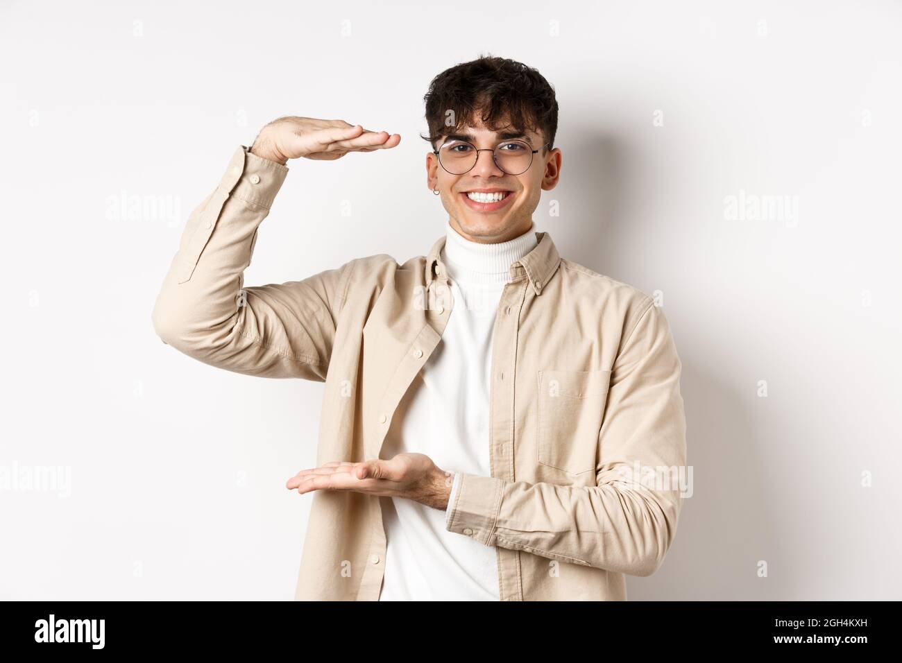 Real people. Happy modern guy in glasses showing big size, shaping box ...