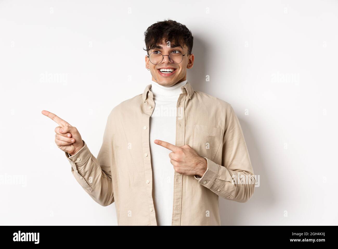 Excited and enthusiastic young man in glasses, pointing fingers and ...