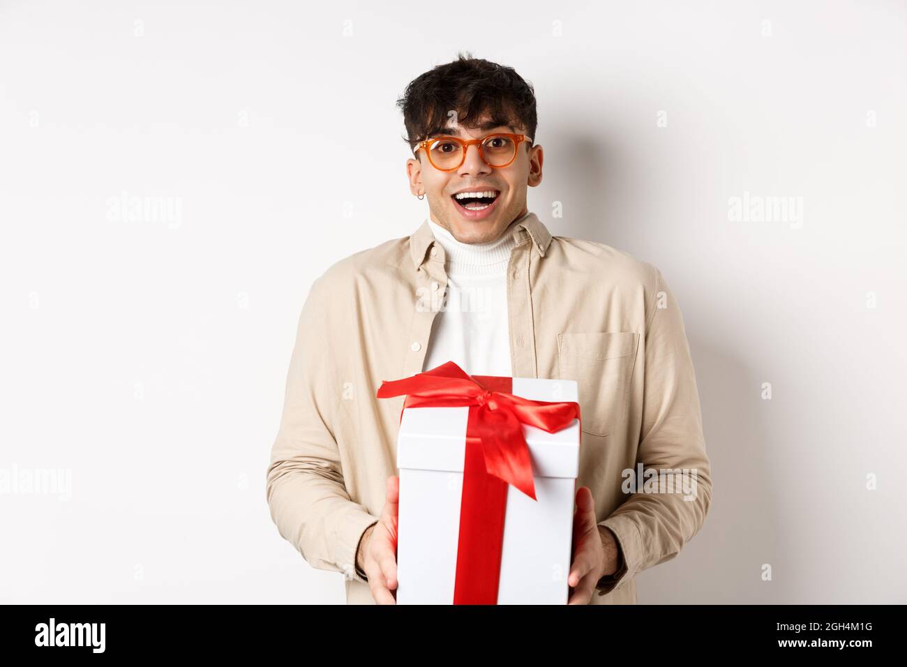 Surprised happy guy receiving a gift, holding present box and smiling ...