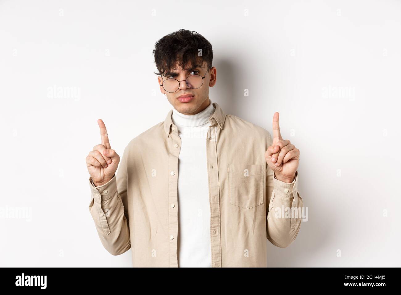 Portrait of young male model in glasses looking suspicious and frowning ...