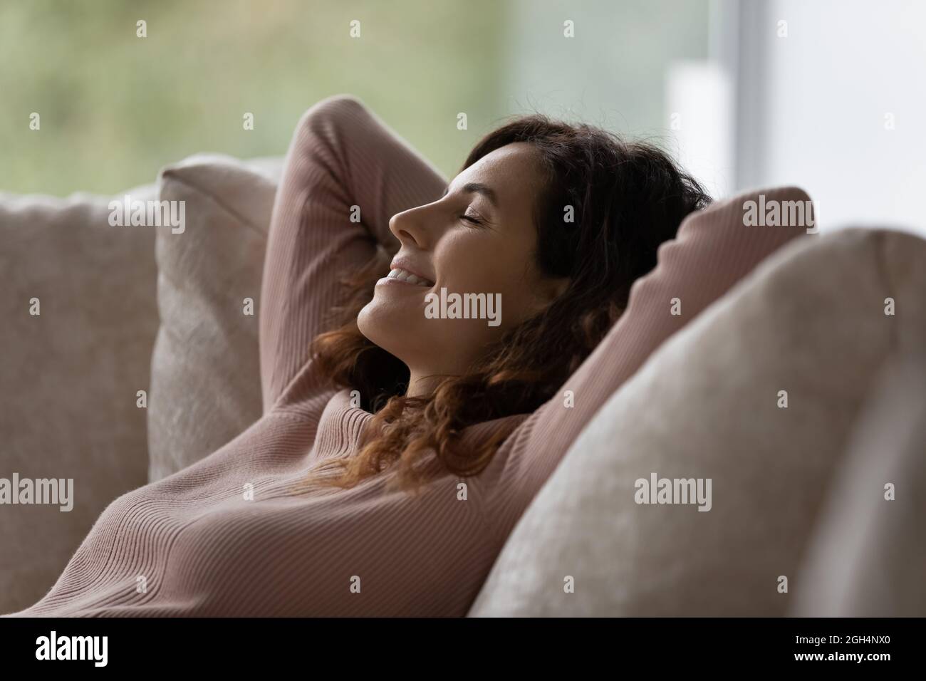 Smiling relaxed hispanic woman sleeping on sofa Stock Photo - Alamy