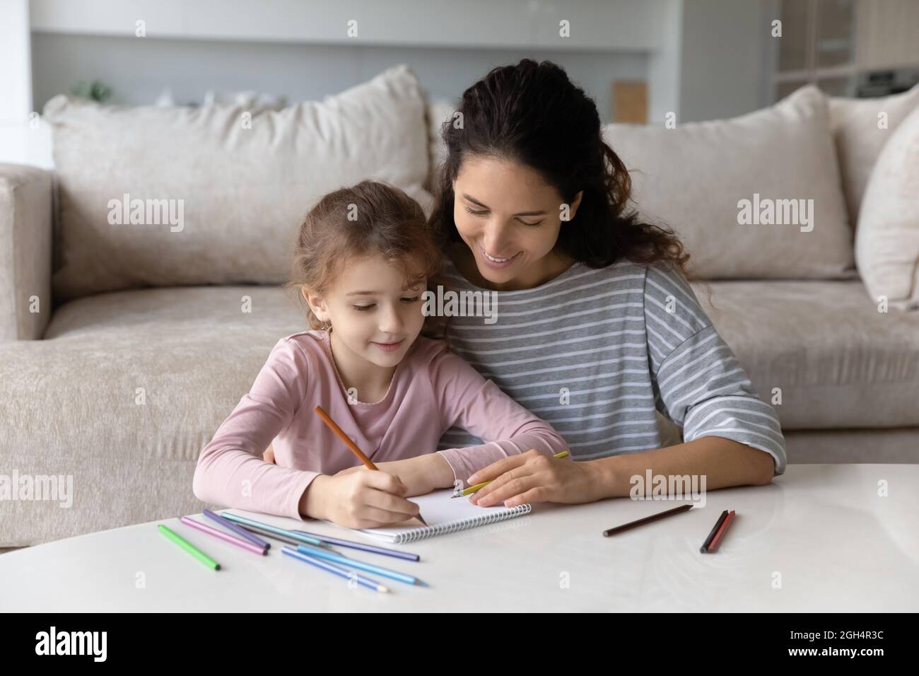 Young mother teaching small daughter writing letters Stock Photo - Alamy