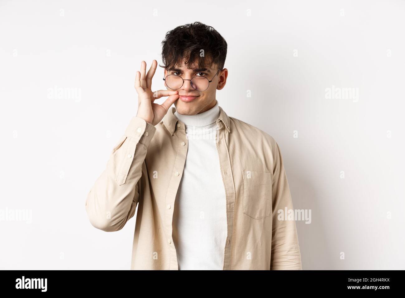 Smiling cunning guy in glasses shut his mouth on zipper, showing seal ...