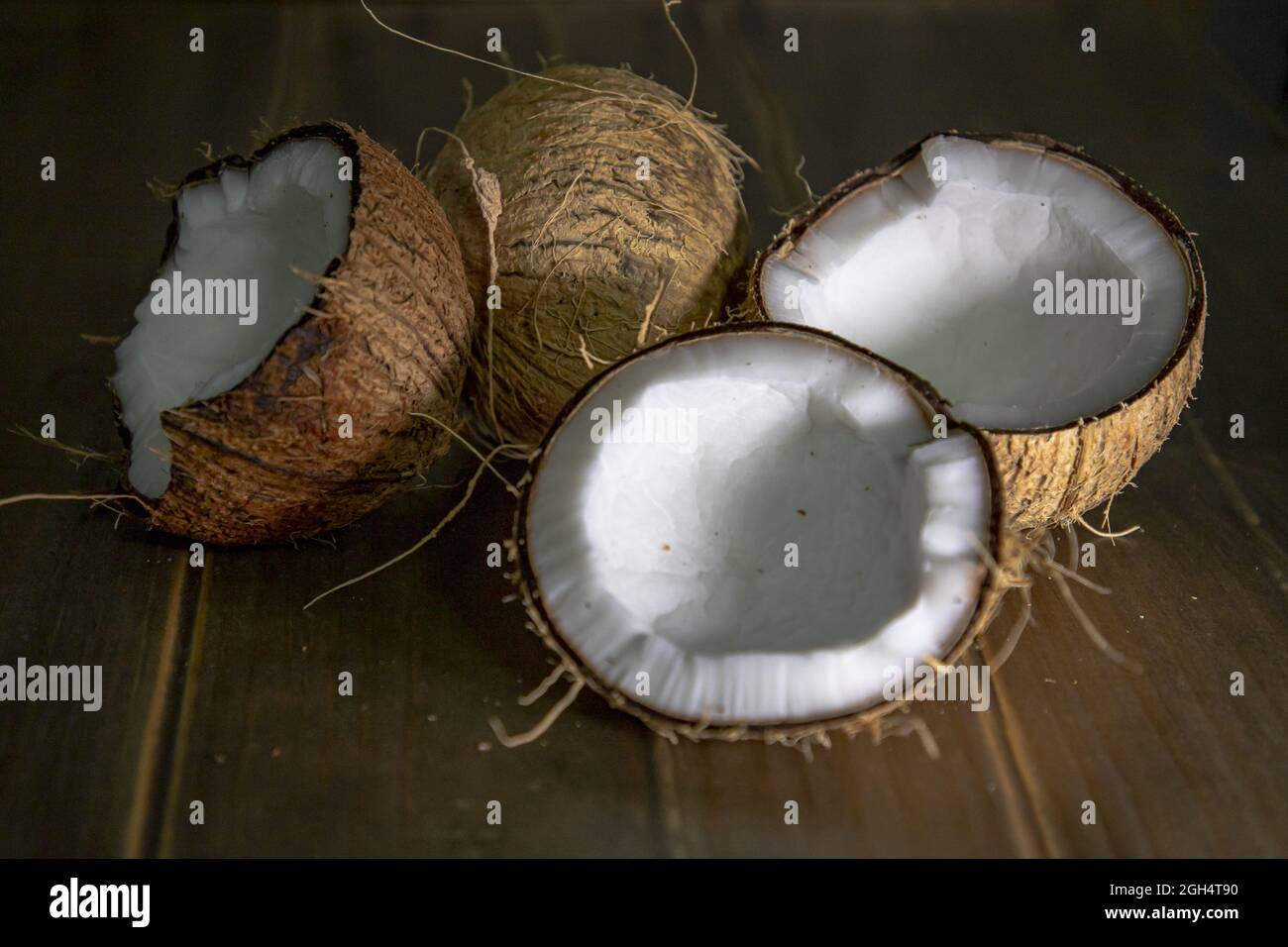 A close up of some opened coconut on brown wooden table Stock Photo - Alamy