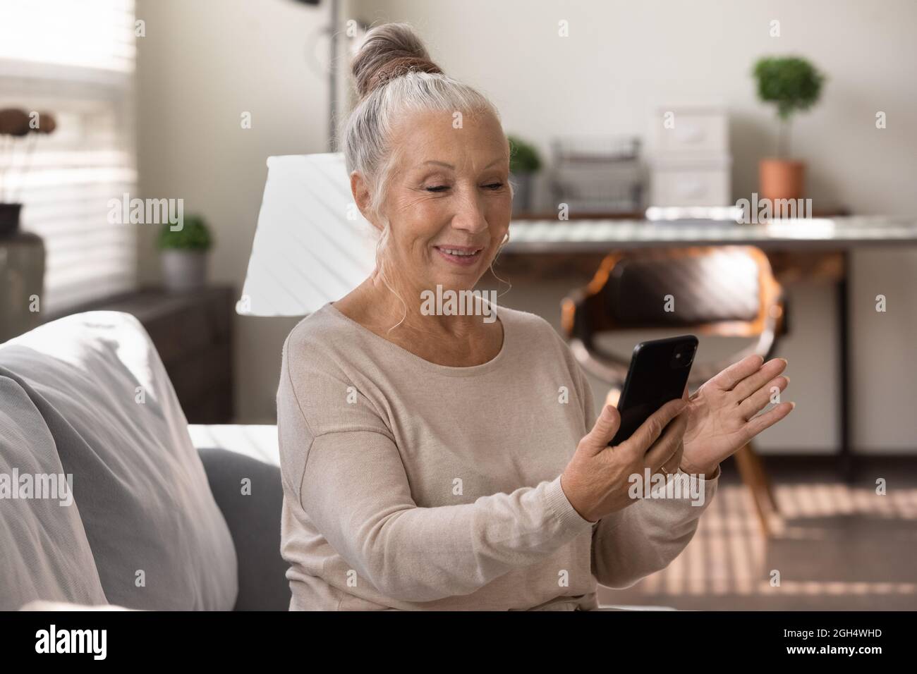 Happy elderly lady using smartphone at home, making video call Stock ...