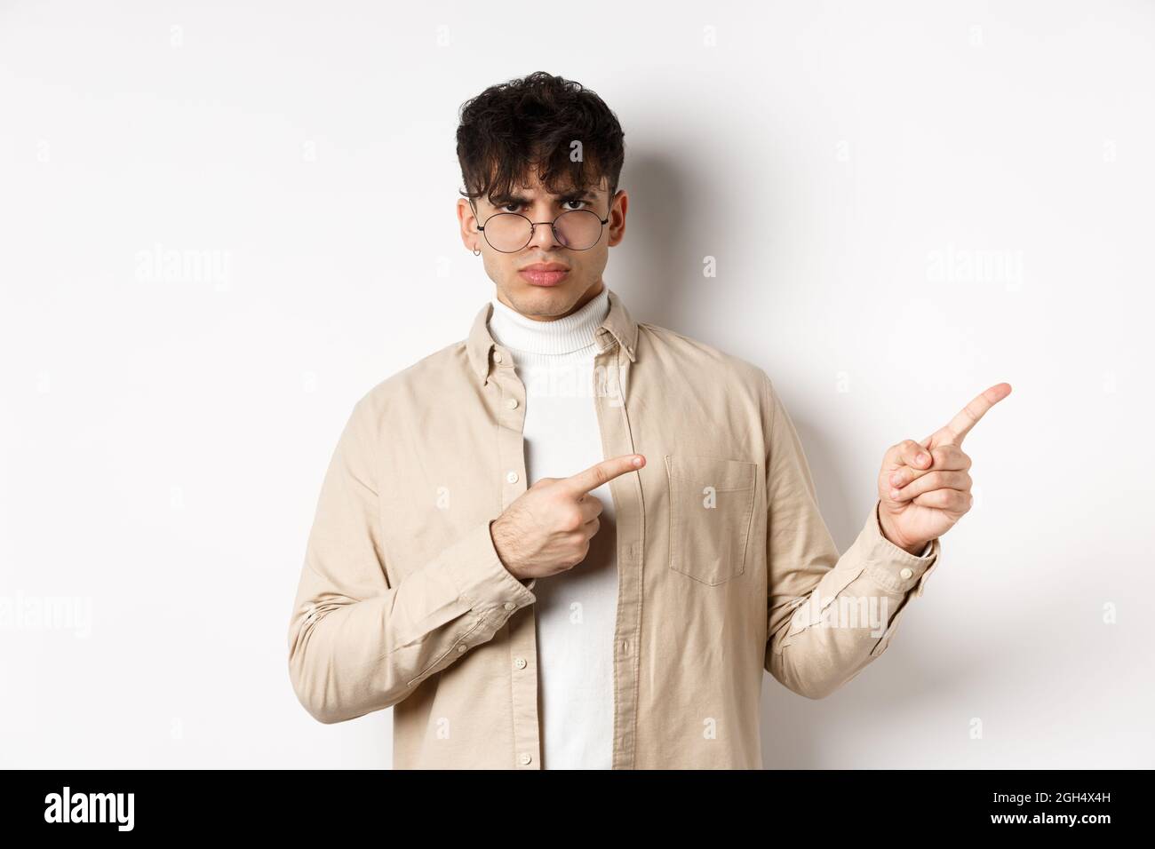 Angry young man frowning and pointing at upper right corner banner ...