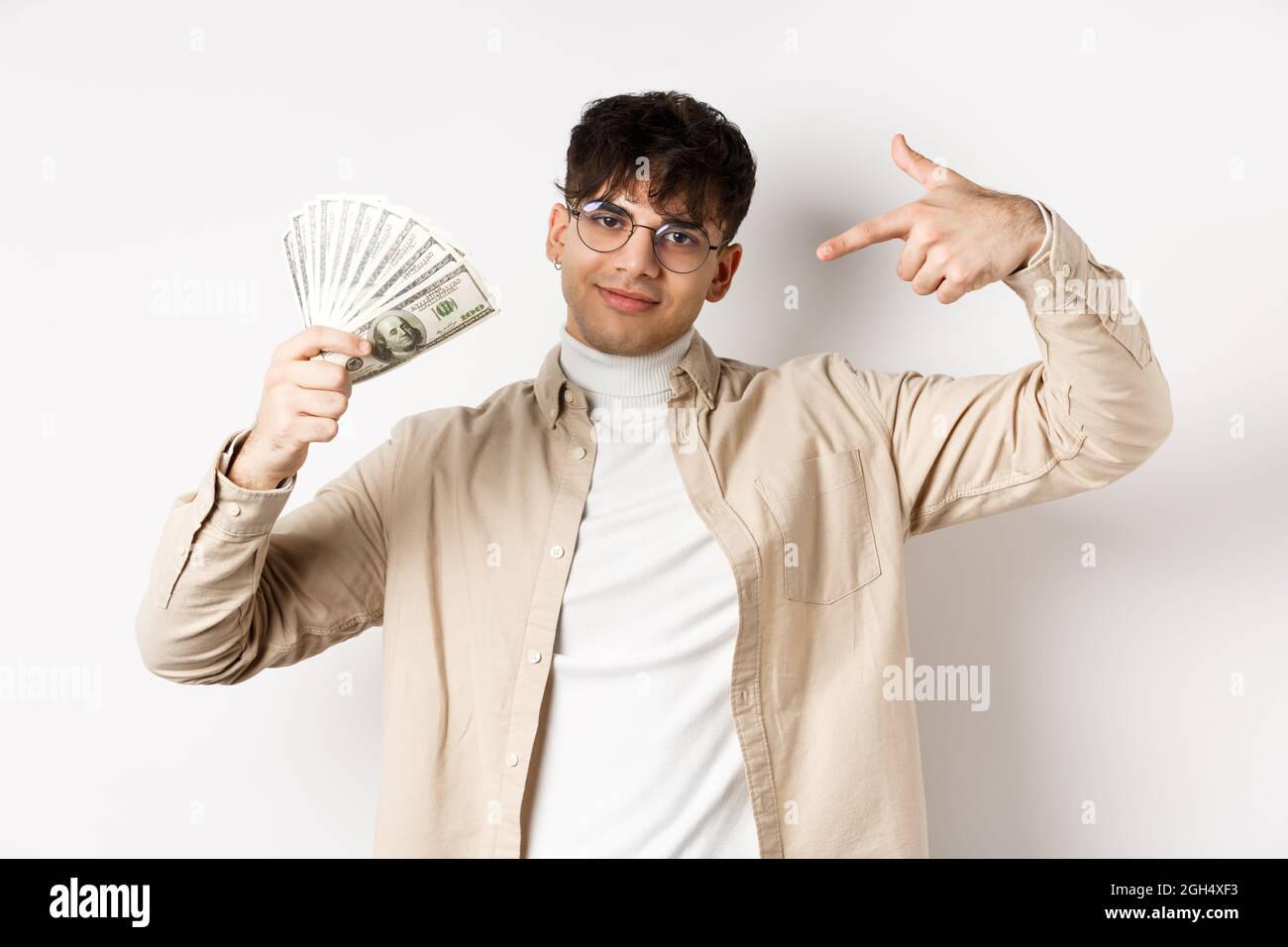 Cool handsome guy show-off his income, pointing at dollar bills and ...