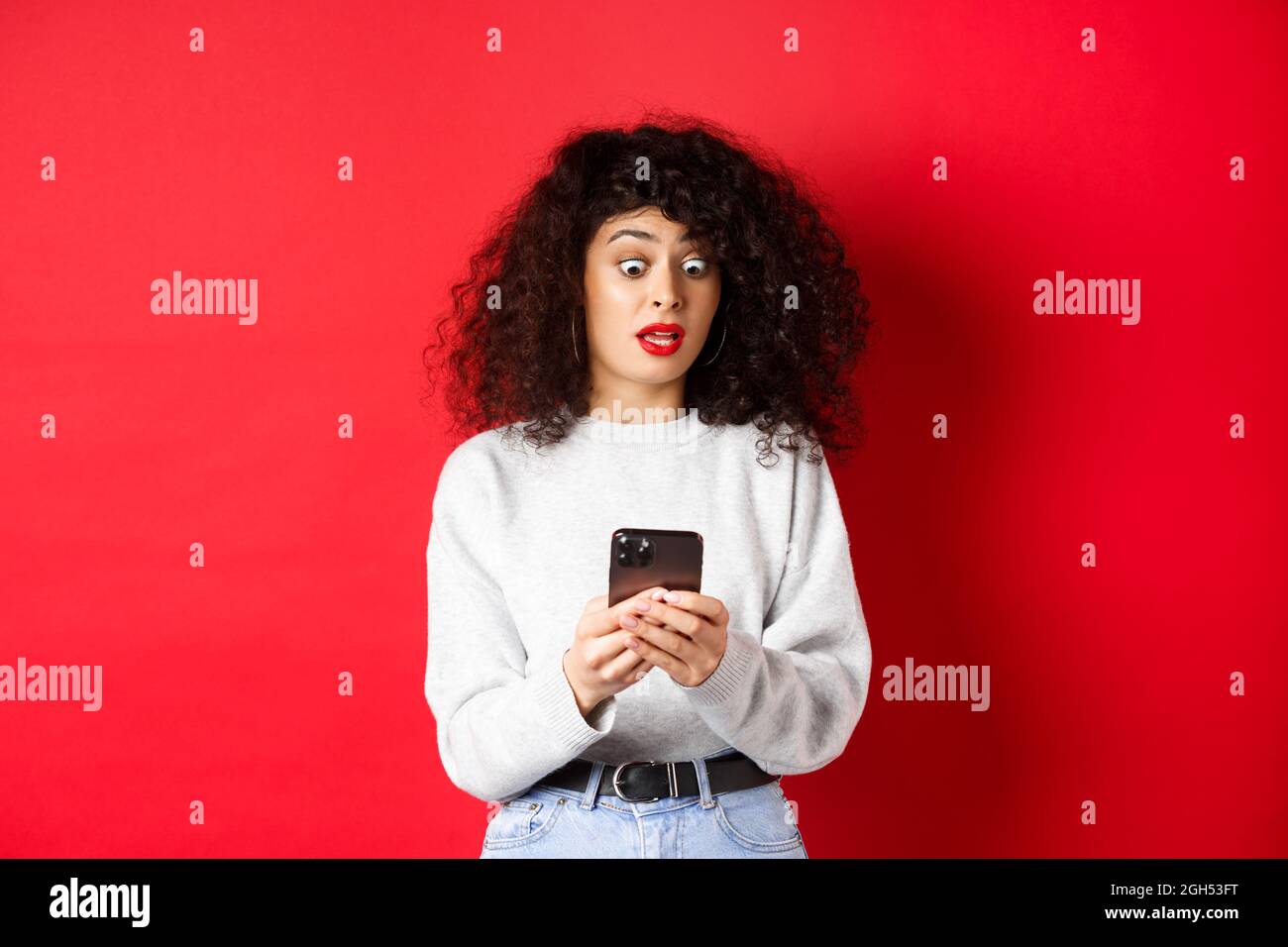 Shocked woman stare at smartphone screen with popped eyes, reading ...