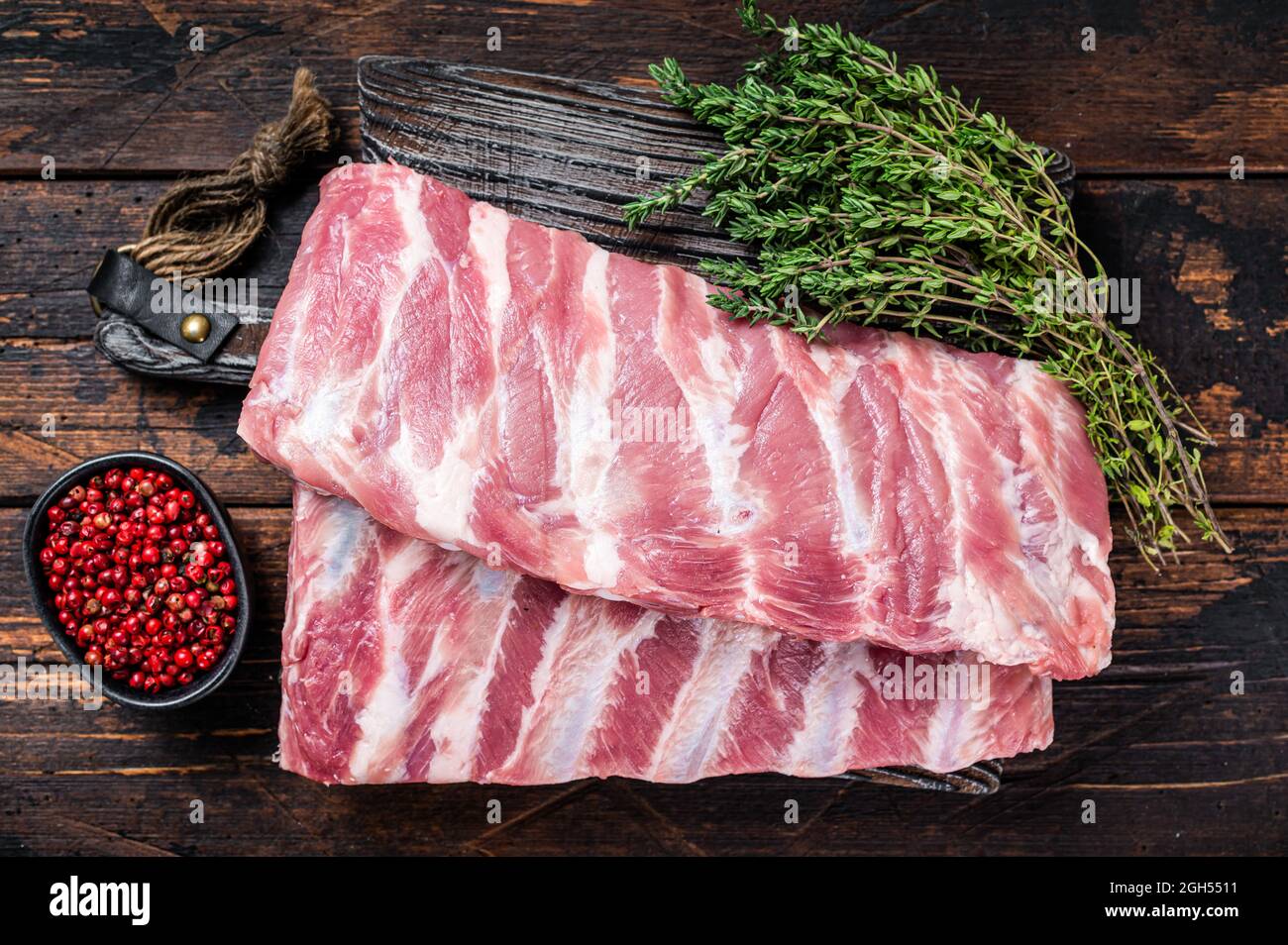 Rack of Fresh Raw pork spare ribs on butcher board. Dark wooden ...