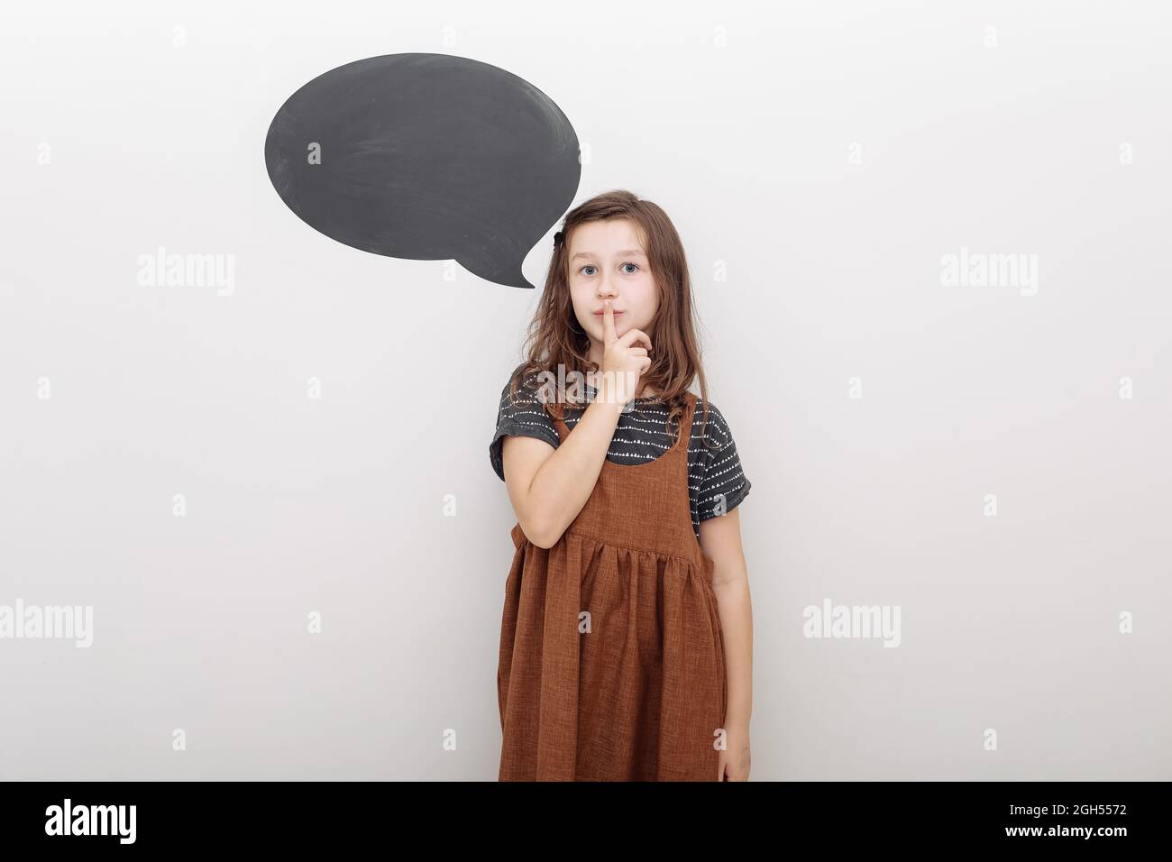 Thoughtful little girl brown-haired child touch chin with finger ...
