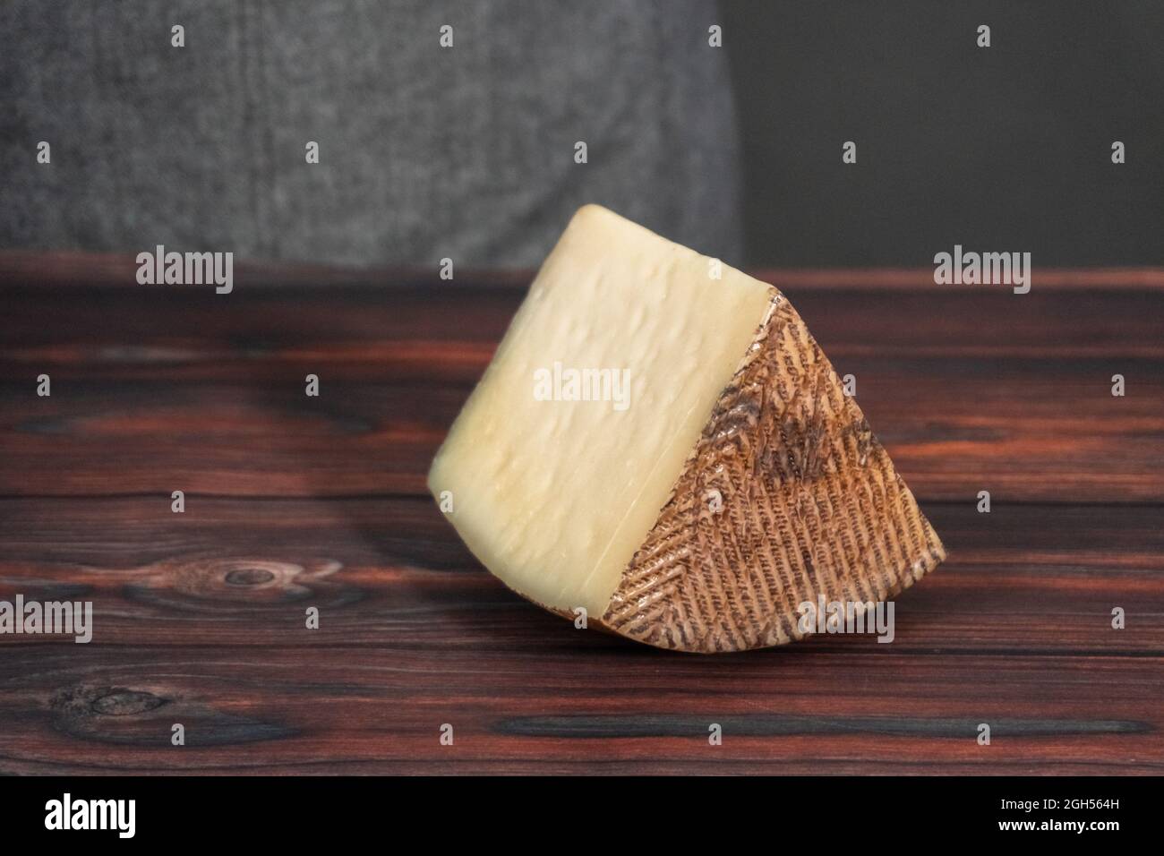 Large wedge of aged Manchego cheese on a dark wooden background Stock Photo - Alamy