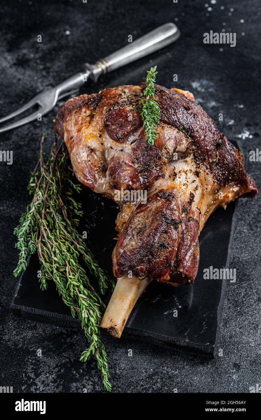 Oven Roasted lamb mutton whole leg with thyme. Black background. Top ...