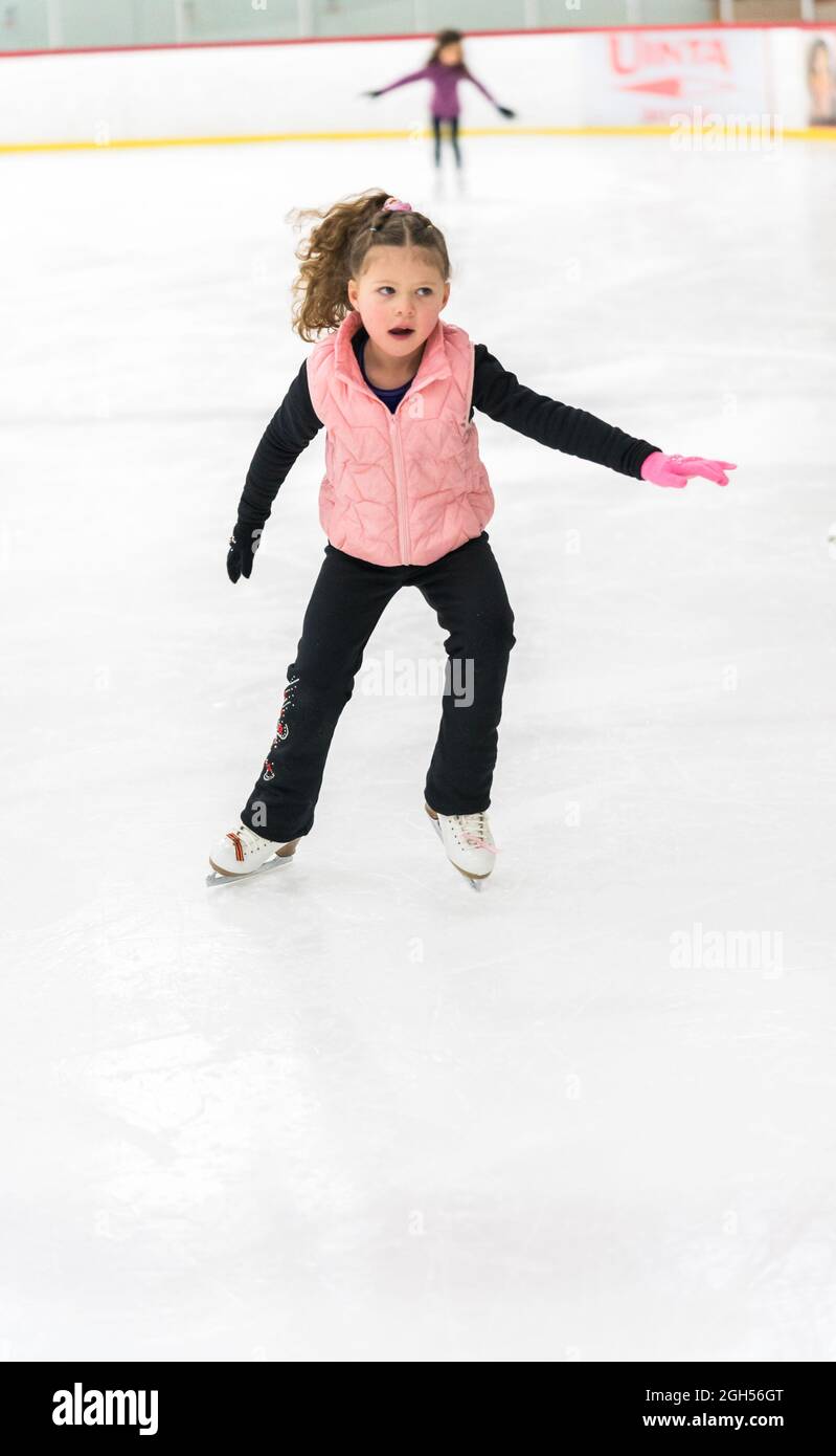 Little girl practicing figure skating elements on indoor ice skating ...