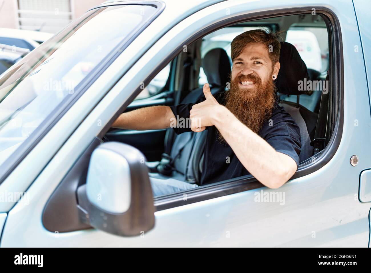 Young irish man smiling happy driving car doing ok sign with thumb up ...