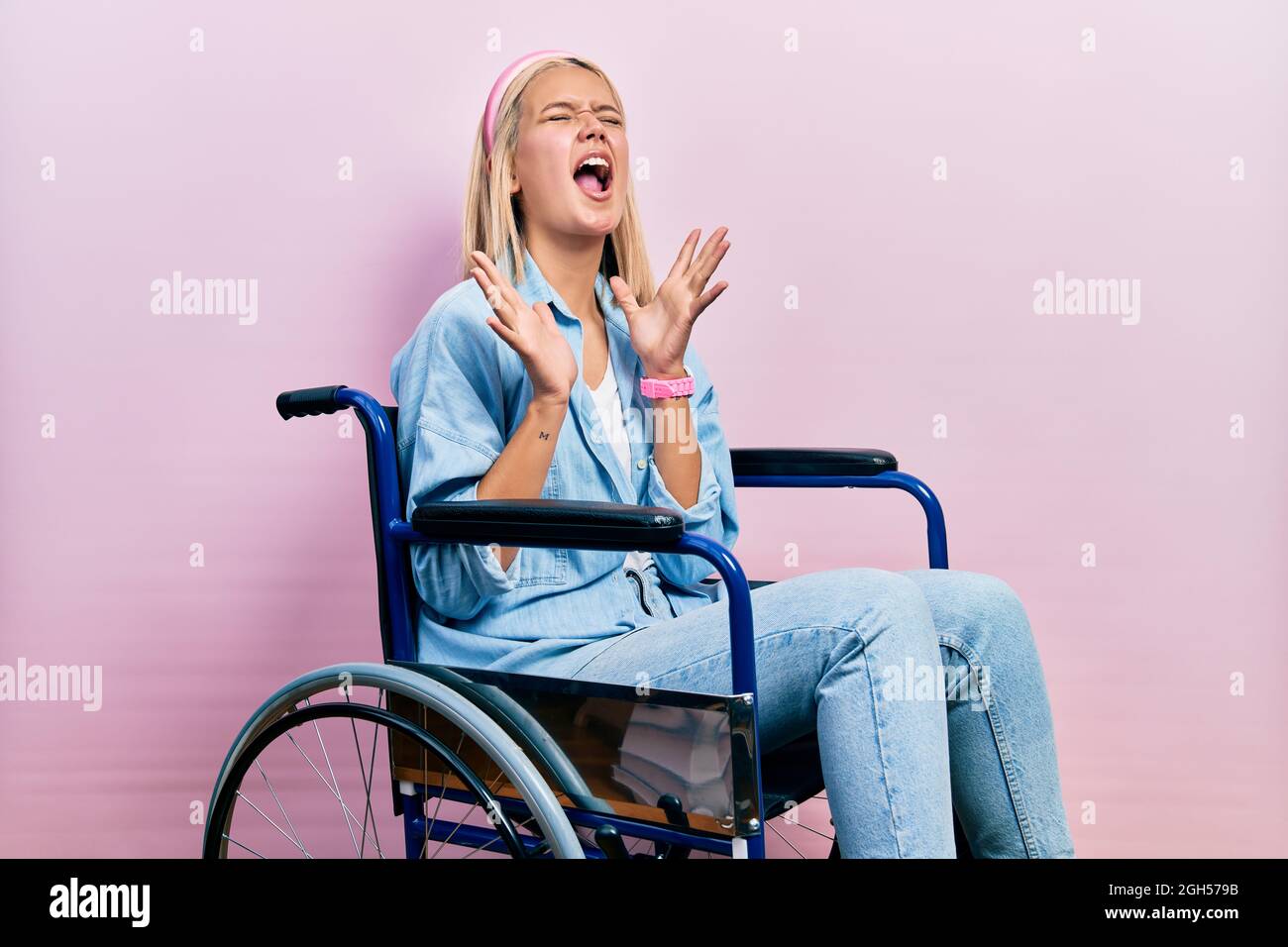 Beautiful blonde woman sitting on wheelchair celebrating mad and crazy ...