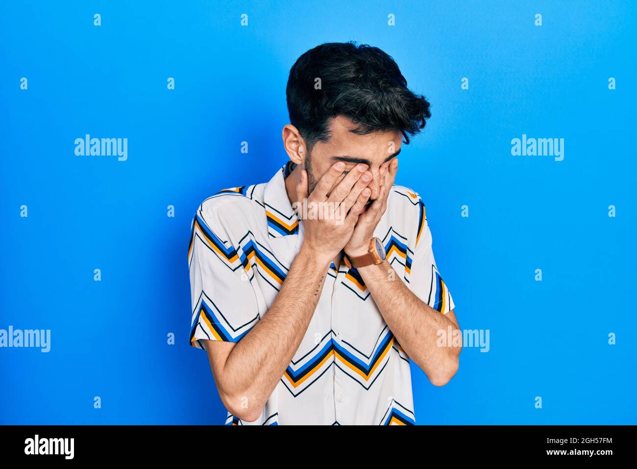 Young hispanic man wearing casual clothes with sad expression covering ...