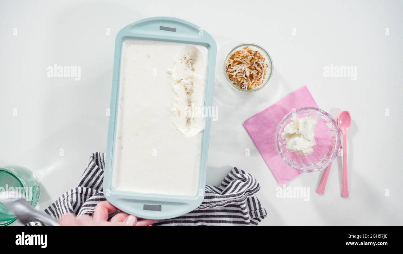 Flat lay. Scooping homemade coconut ice cream into a glass ice cream ...