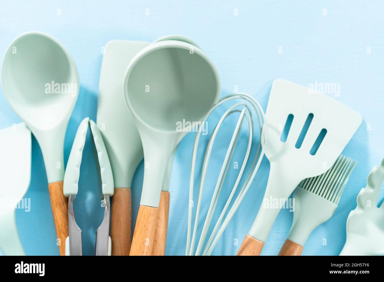 New blue silicone kitchen utensils with wooden handles on a blue ...