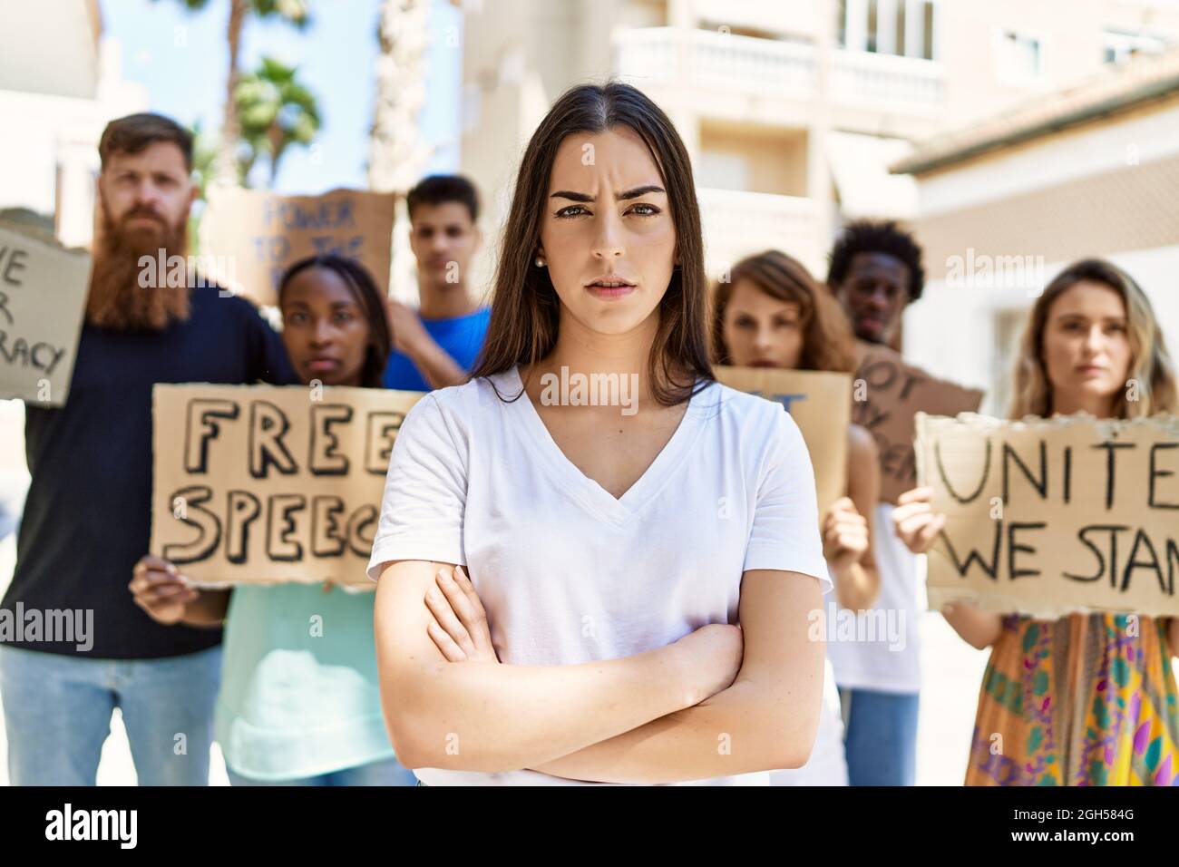 Young activist woman with arms crossed gesture standing with a group of ...