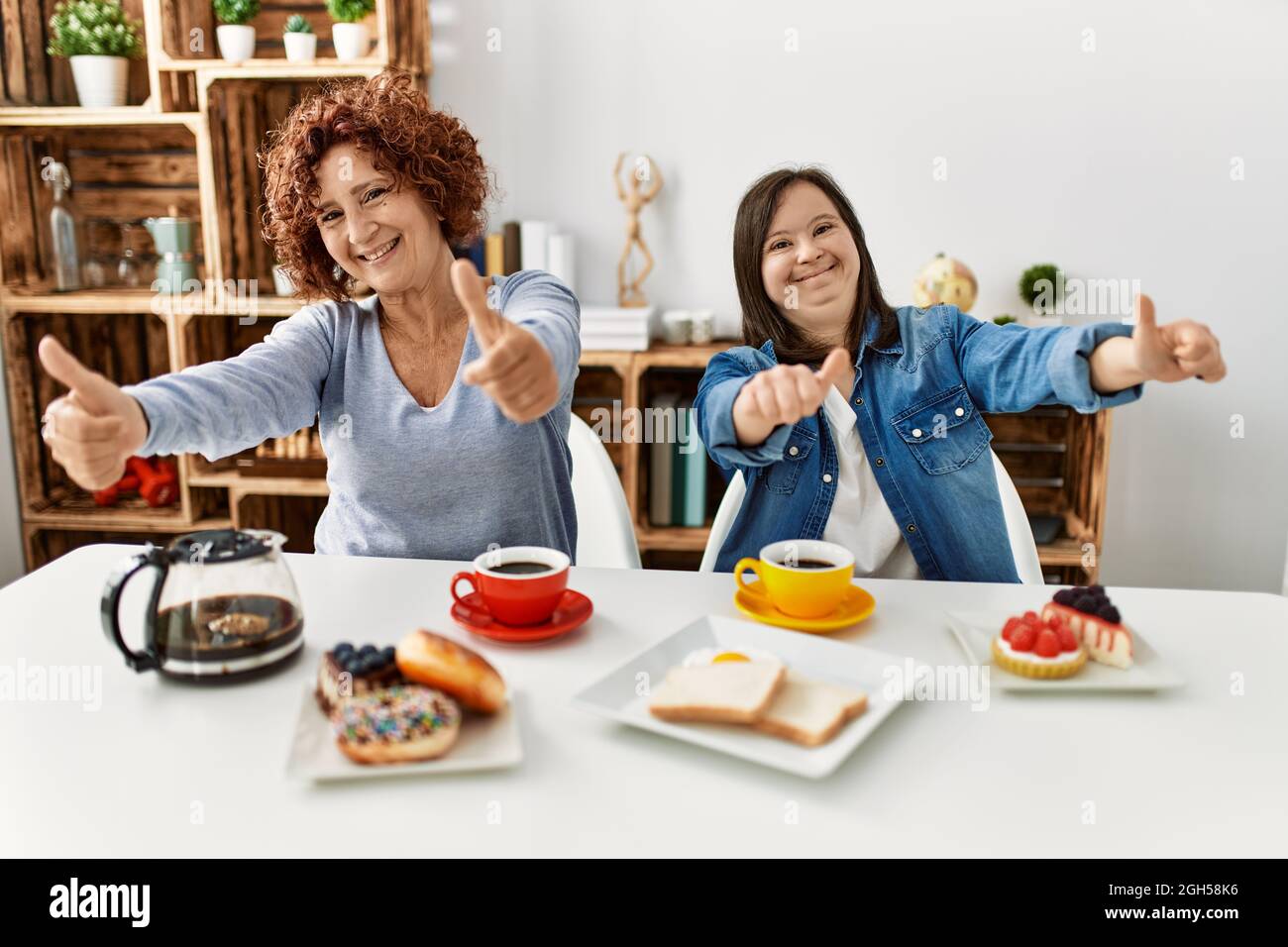 Family of mother and down syndrome daughter sitting at home eating ...