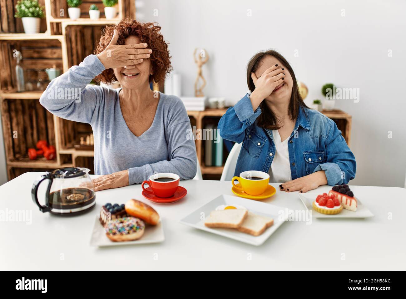 Family of mother and down syndrome daughter sitting at home eating ...