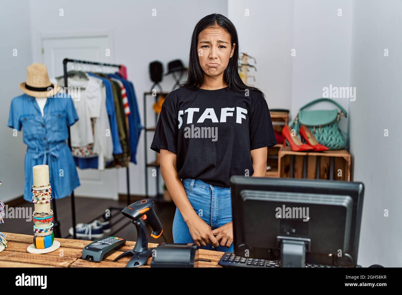 Young hispanic woman working as staff at retail boutique depressed and ...